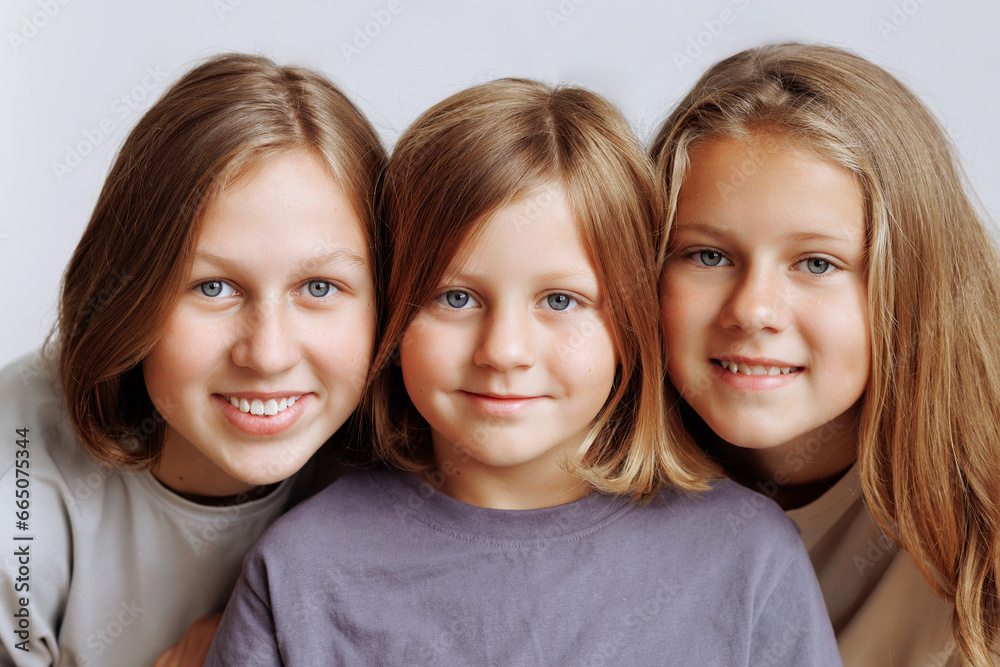 The faces of three sister girls close-up on a white background. They ...