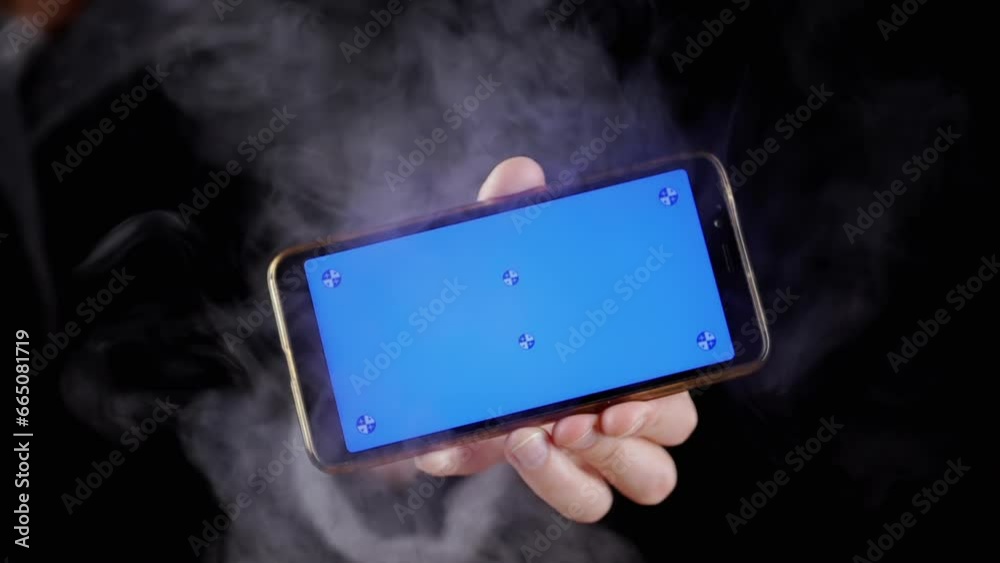 Hand Holding a Mobile Phone with a Blue Screen on a Black Background in ...