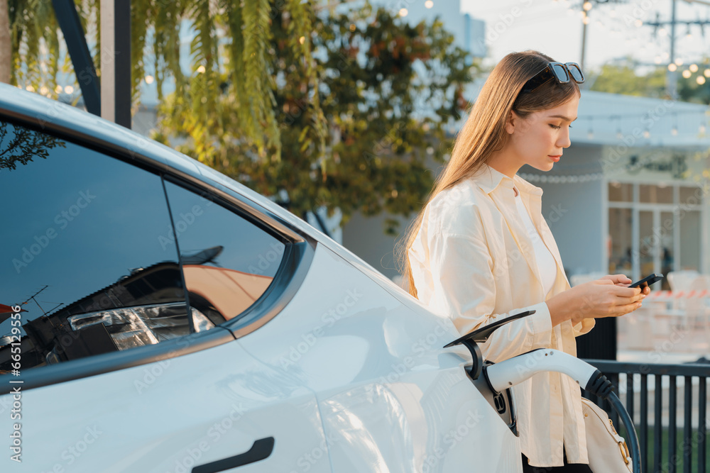 Sustainable urban commute with young woman pay electricity for EV ...
