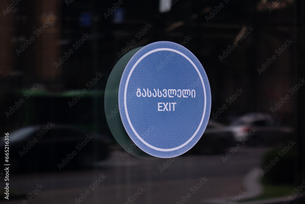 Round blue sign with text behind glass door of store. Window of city ...