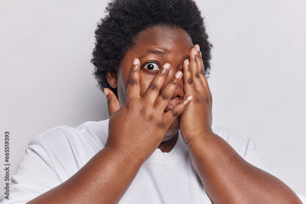 Shocked scared overweight young African woman with curly hair covers ...