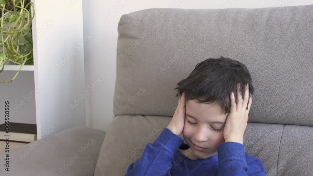 Child scratching head sitting on a sofa in the living room . Annoying ...