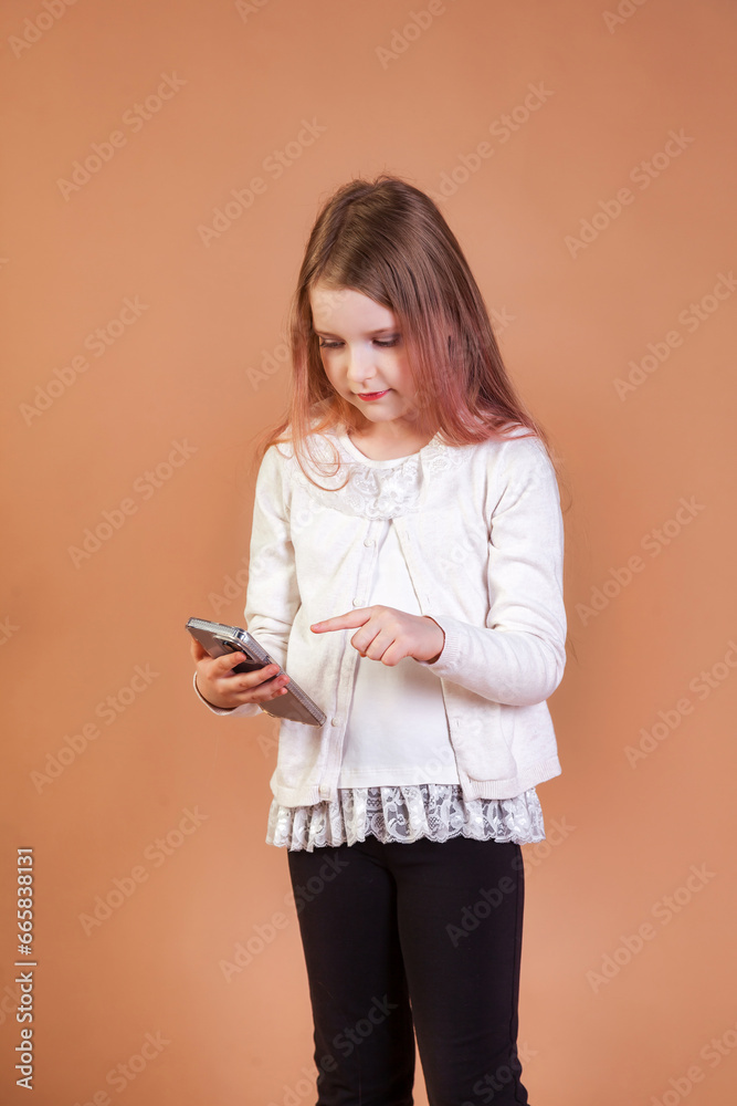 Pensive kid girl in white using texting sms at mobile phone posing at ...