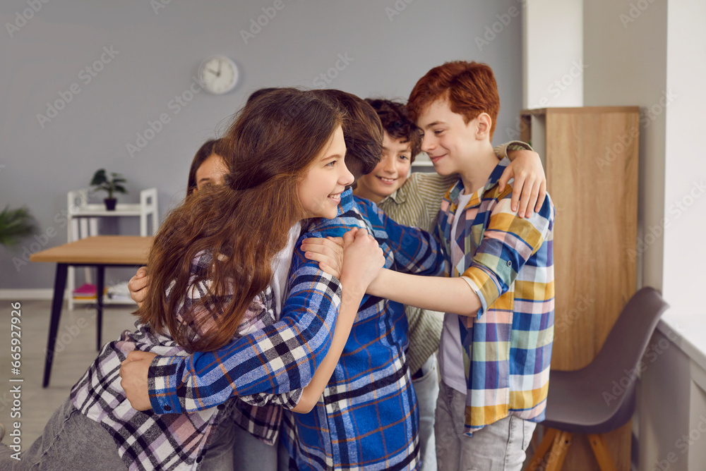 Happy friends and classmates hugging in the classroom. Several school ...