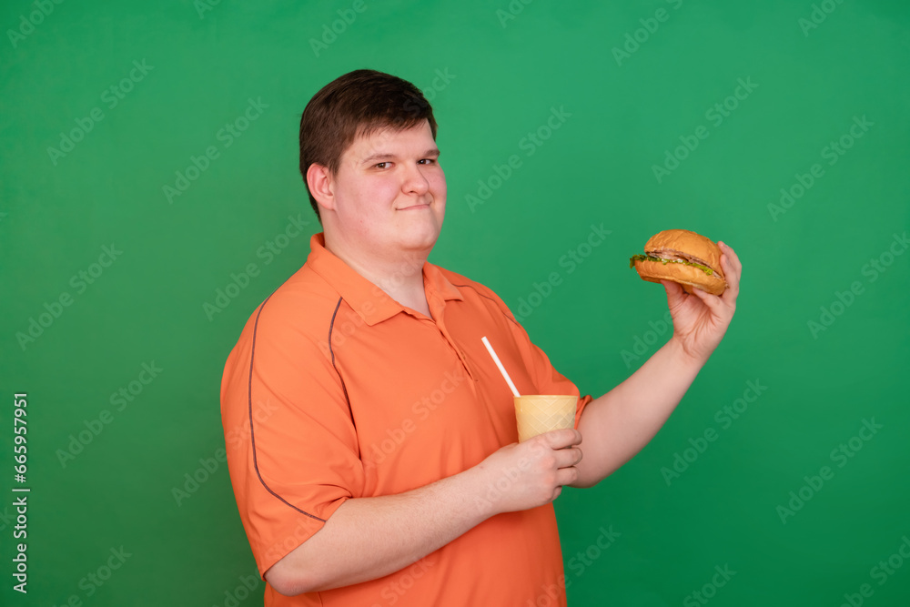 Portrait of a fat guy eating a big hamburger and drinking soda from a ...
