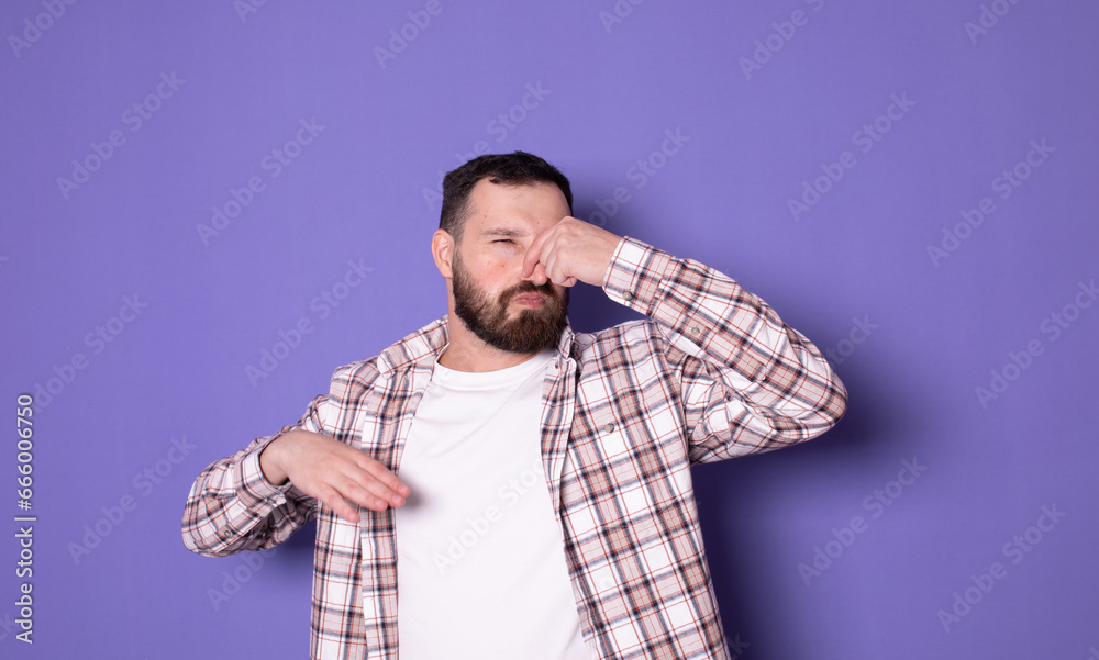 Bad smell. Young bearded man on purple background wearing casual ...