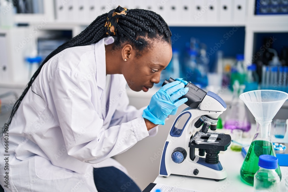 African american woman scientist using microscope at laboratory Stock ...