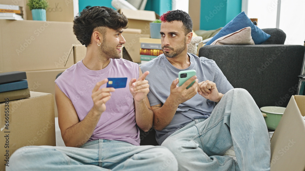 Two men couple shopping with smartphone and credit card at new home ...