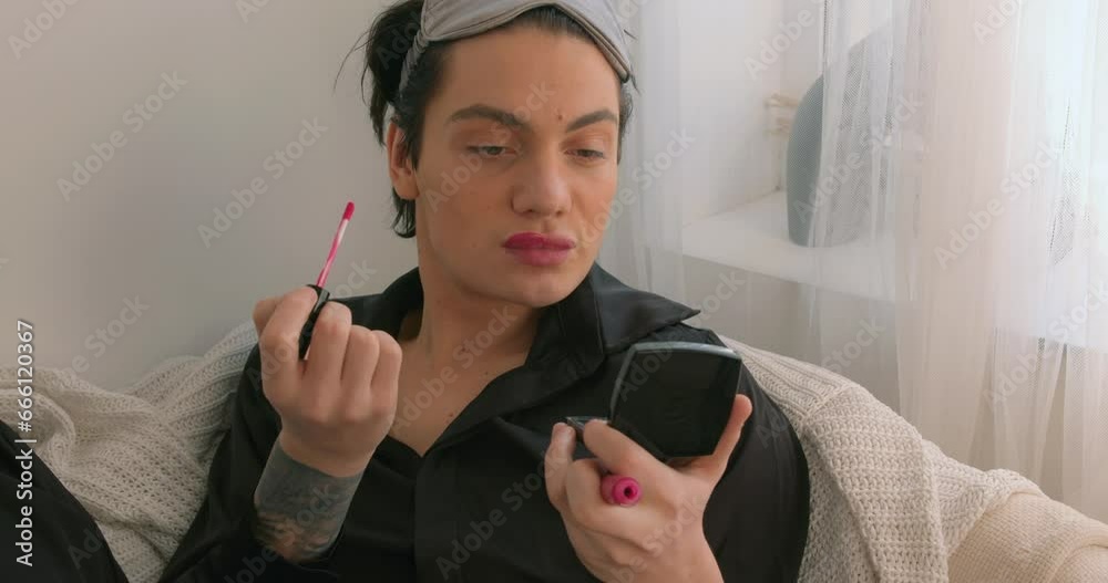 transgender male model applying lip gloss while doing makeup. slow ...