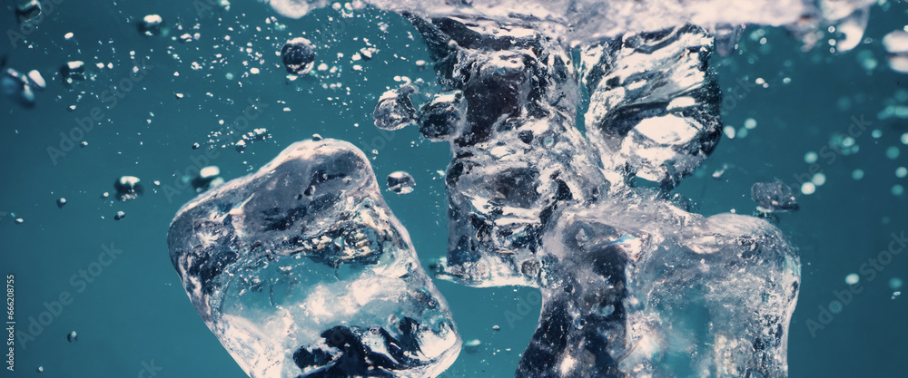 Water splashing and ice cube. Ice splashing into a glass of water. Underwater pouring ice cubes ...