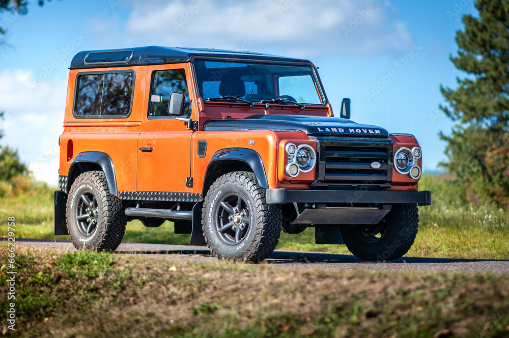 Orange Land Rover Defender 90 SUV parked on the road. Car side view ...