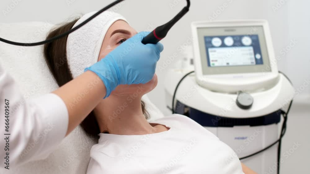 Close-up of a young woman's face during microcurrent therapy. Procedure ...