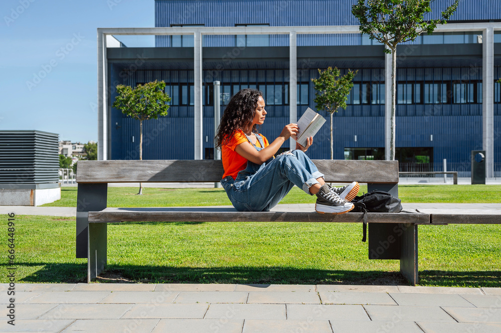 Young student sitting on bench and studying in front of building Stock ...