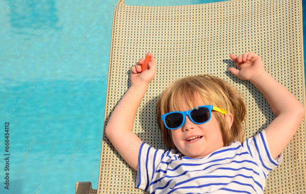 Cute boy relaxing in a sun lounger near the pool at the hotel. Family ...