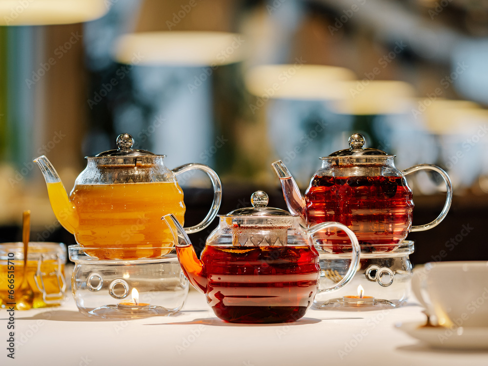 Set of three transparent glass teapots with warmer and candles, hot ...