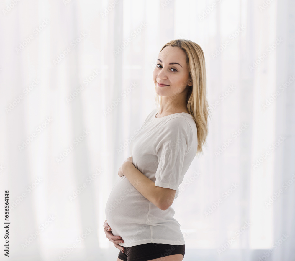A pregnant woman in a white T-shirt and short shorts stands near a ...