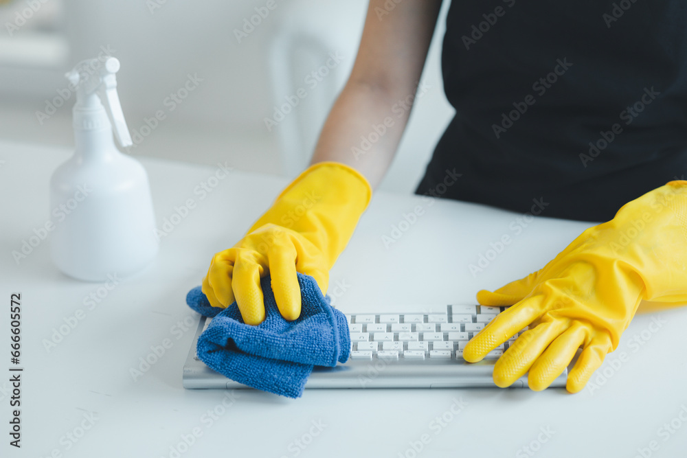 Cleaning staff wiping down office equipment, Wipe the keyboard clean ...