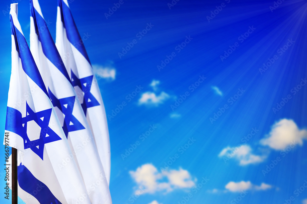 Israel flags against a background of a cloudy blue sky with rays of sun ...