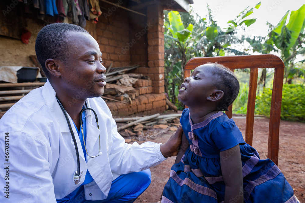 African doctor talking to a sick baby girl during a visit in a rural ...