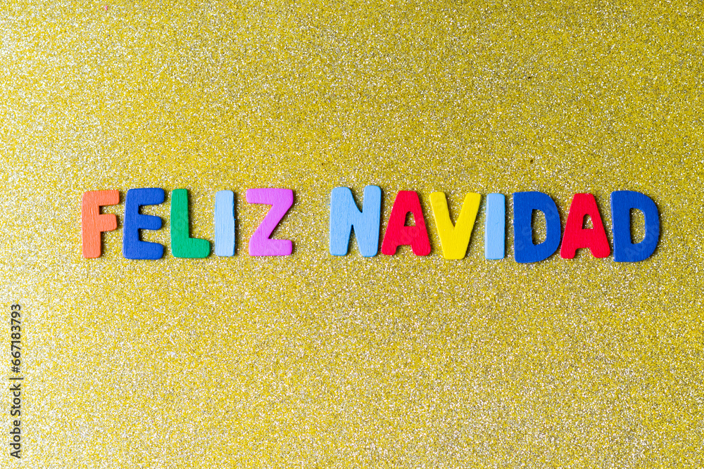colorful letters with the phrase Merry Christmas in Spanish on a golden ...