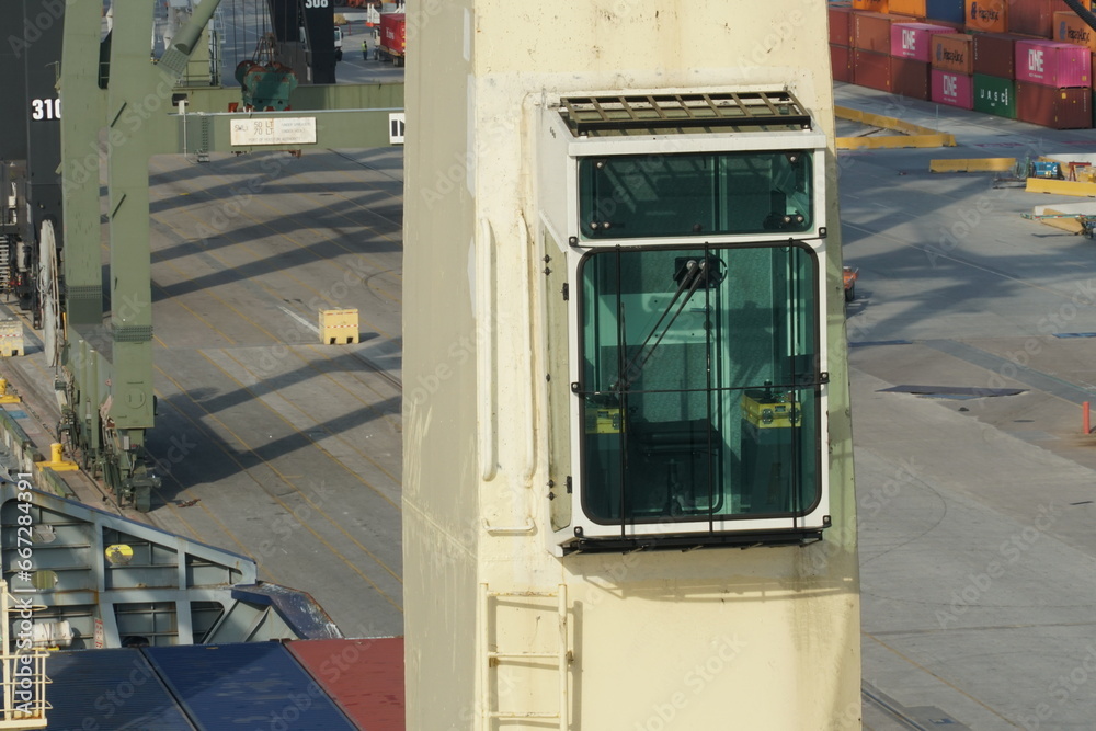 Cream cabin of ship crane operated by crew on container vessel moored ...