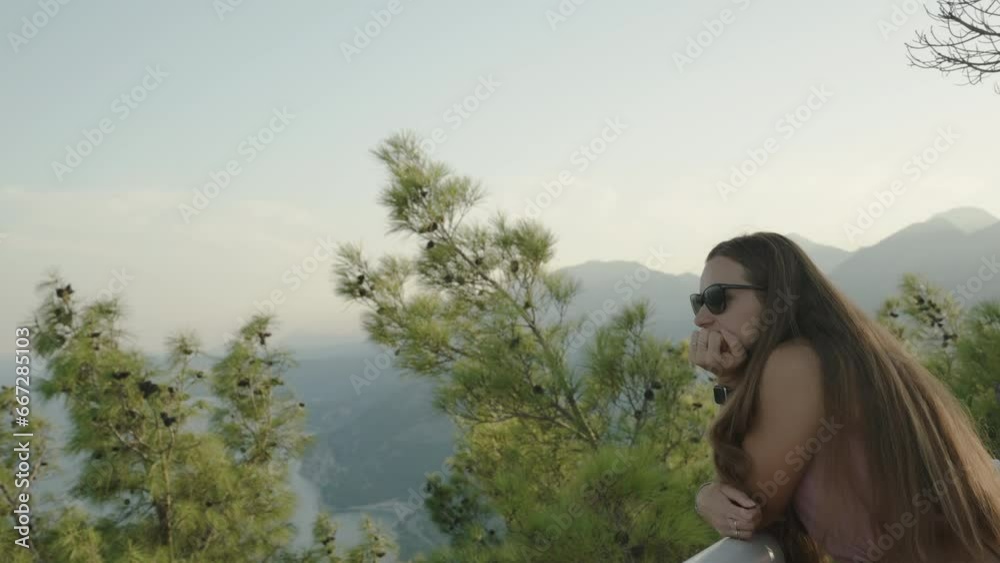 The traveling young woman approaches the edge of the cliff. Leaning on ...