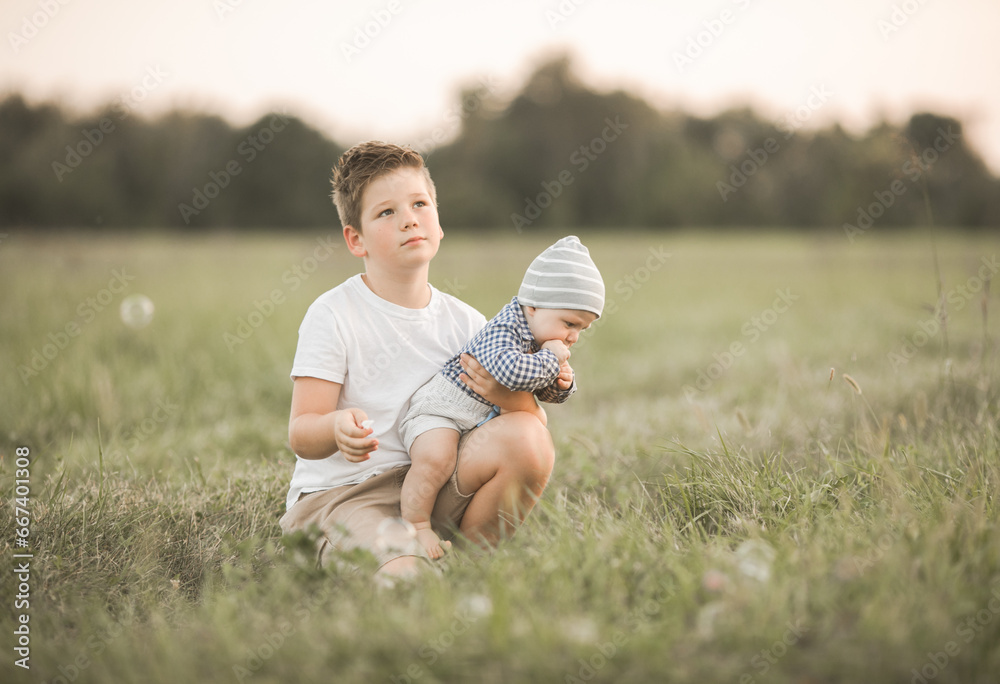 Cute boys outside, older brother hugs younger, taking care of sibling ...