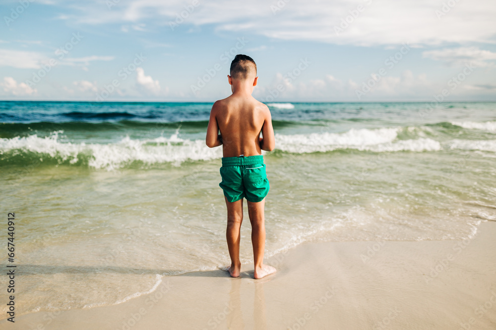 Boy facing ocean while waves are coming in on a summer day Stock Photo ...