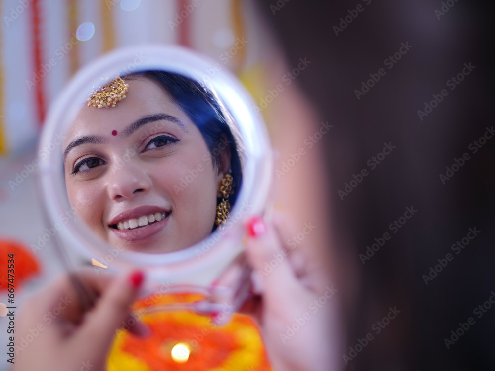 A beautiful Indian woman putting a small red bindi on her forehead and ...