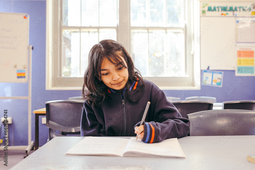 Girl student sitting at her desk in a classroom doing her schoolwork ...
