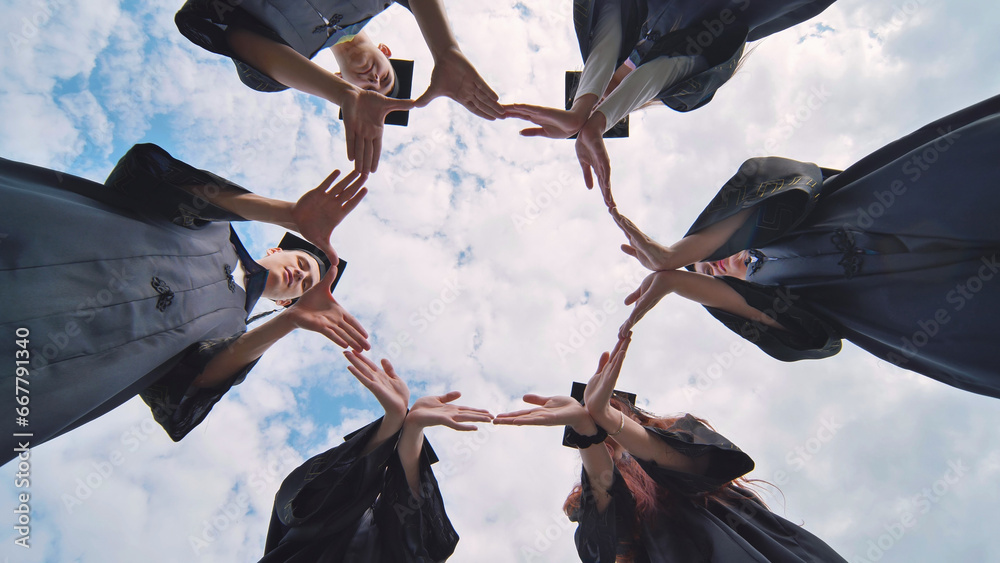 Graduate students in black robes and caps make a circle shape from ...