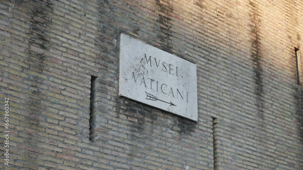 Close-up low-angle view of sign pointing to Vatican museums on brick ...