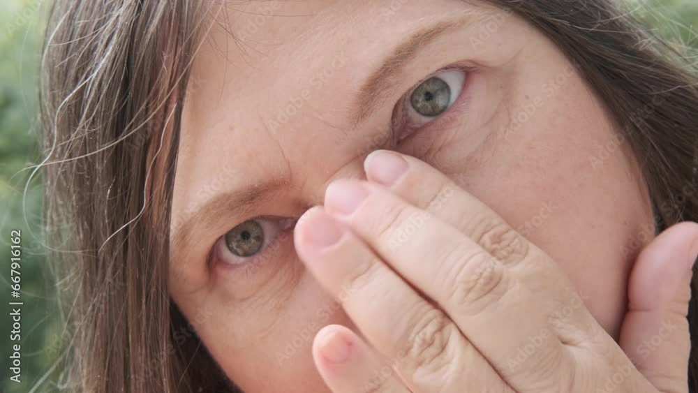close up of mature female face, woman 50 years old carefully examines ...