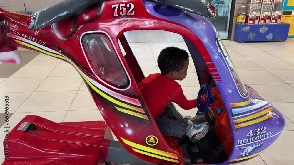 3-year-old black kid enjoying in a coin-operated ride in a helicopter ...