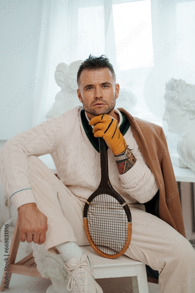 Dapper man in old money style attire striking a pose with a tennis ...