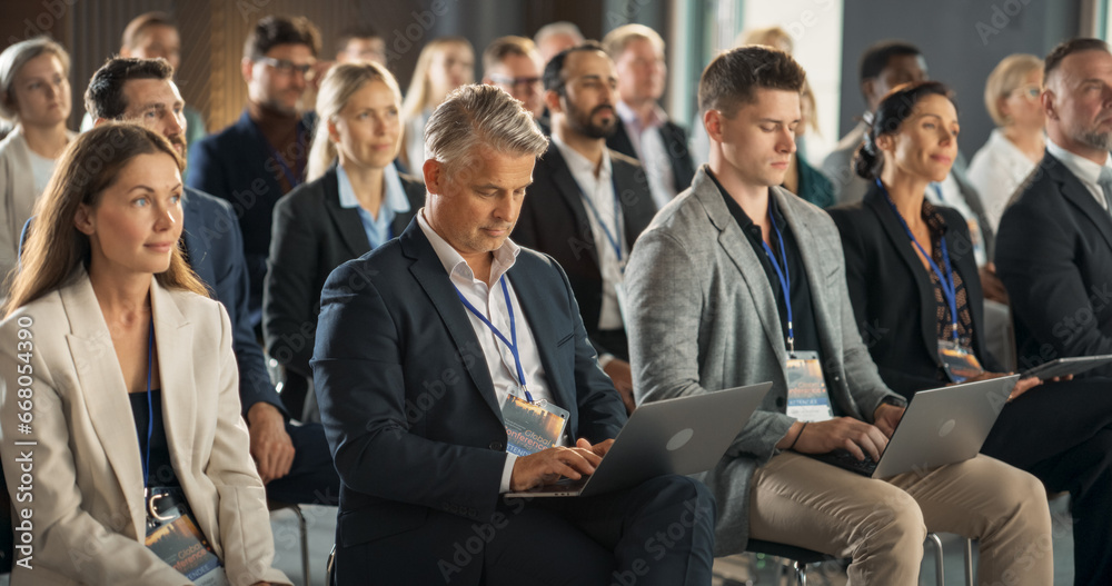 Caucasian Male CEO Sitting In Diverse Crowd Of Business Leaders At ...