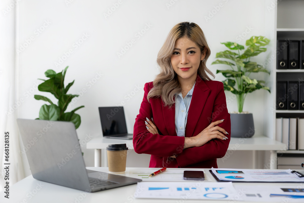 Attractive Asian female accountant wearing formal red suit calculating ...