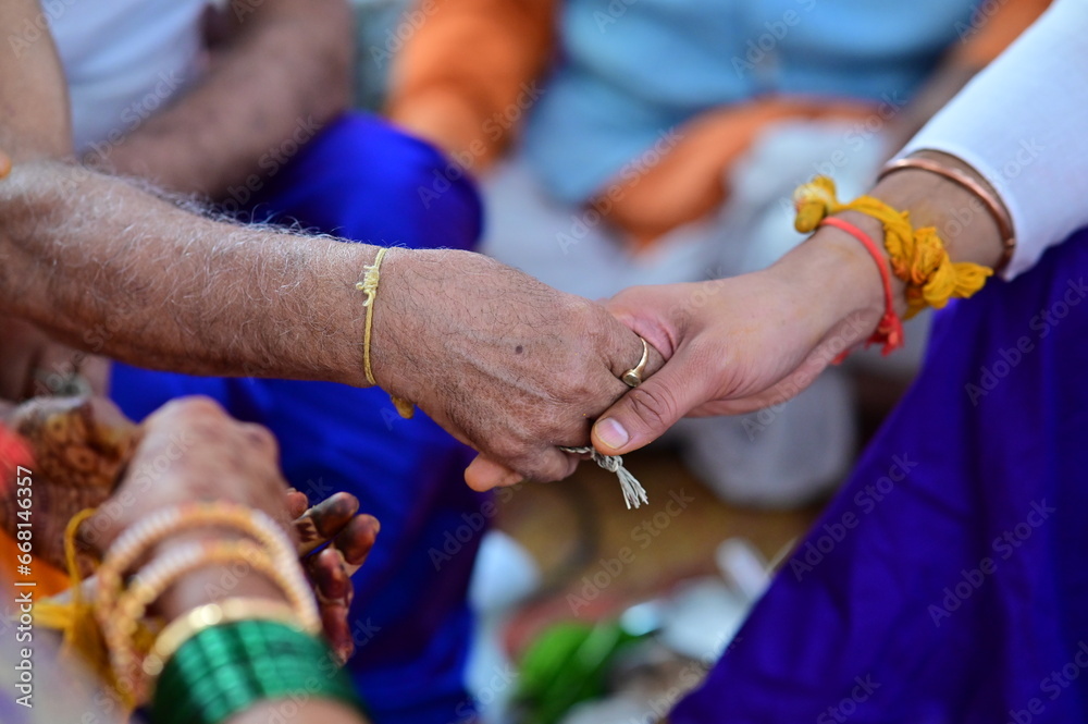 Groom hand with turmeric thread hold hand on bride's father. indian ...