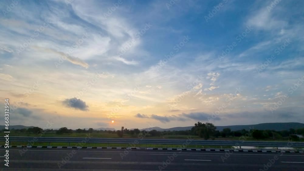 side view of road trip with signs rushing past, fluffy monsoon clouds ...