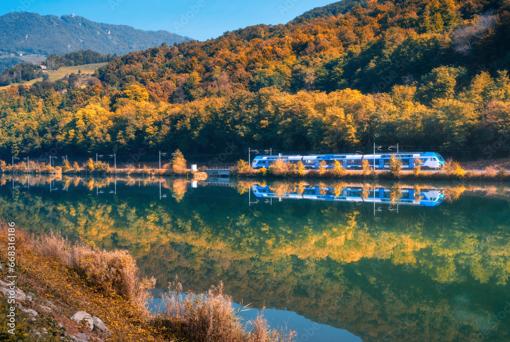 Beautiful blue modern high speed train and river in alpine mountains at ...
