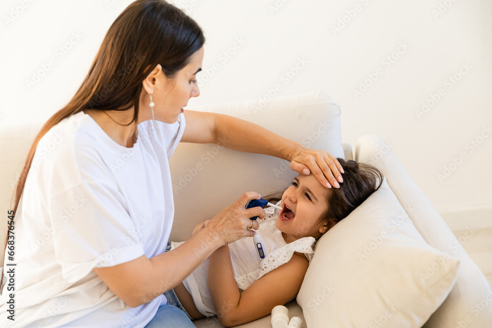 Mom treats her little daughter's cold and throat by spraying the medicine into the child's mouth ...