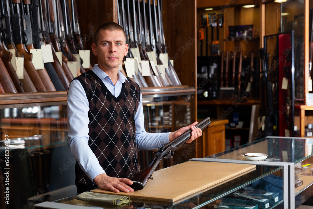 Portrait of gun store salesman showing collectible old rifled musket on ...