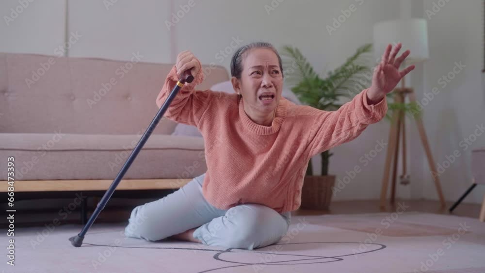 An elderly Asian woman, holding a walking cane, attempts to rise from ...