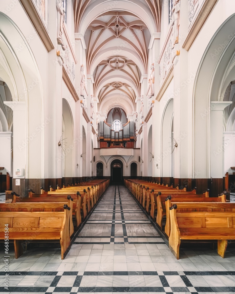 the interior of a church, with two rows of wooden pews in between them ...