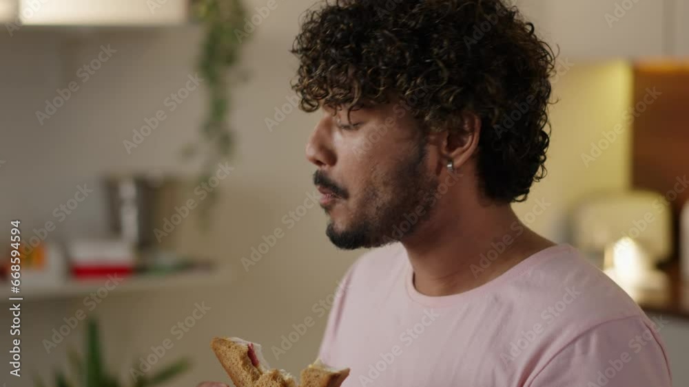 Concept of cheat meal. Young indian man eating big sandwich and ...