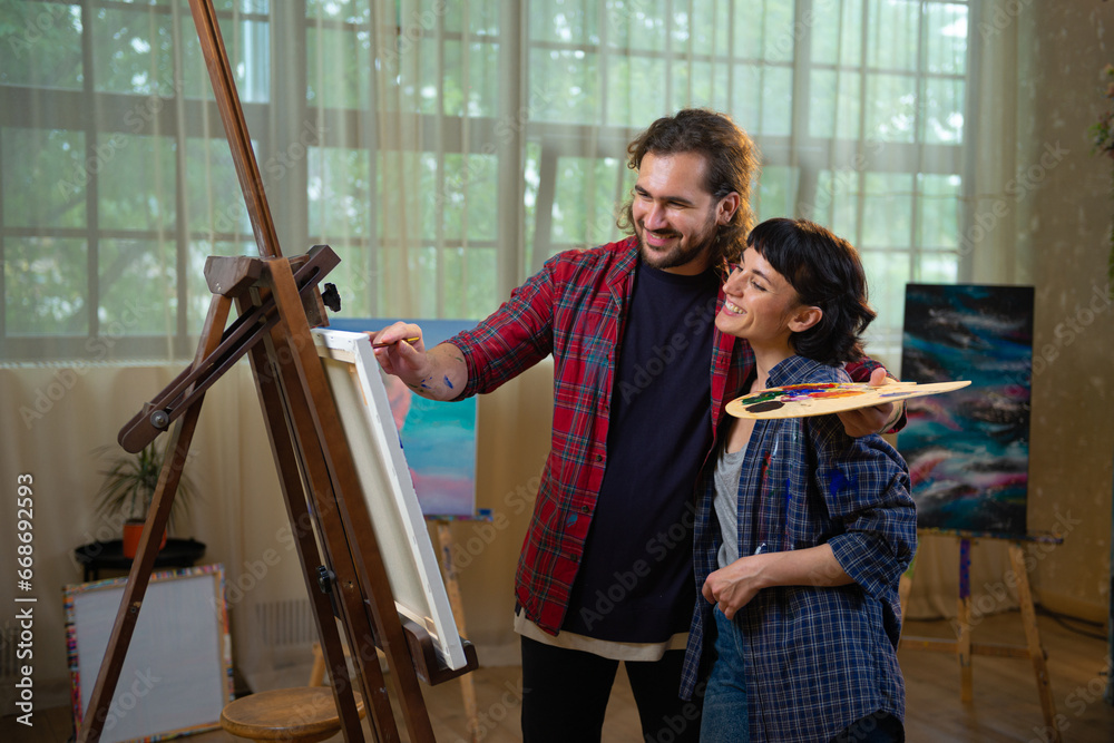 Couple of Artists Sitting in their Studio Use Laptop Computer, Working ...