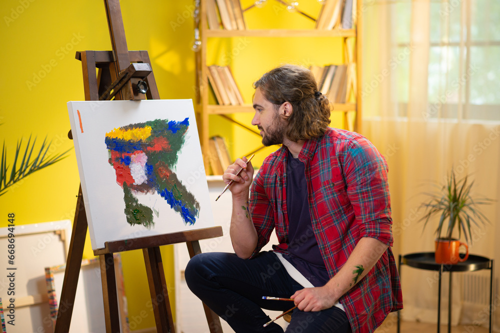 A very good looking man is painting a rare and modern painting and he ...