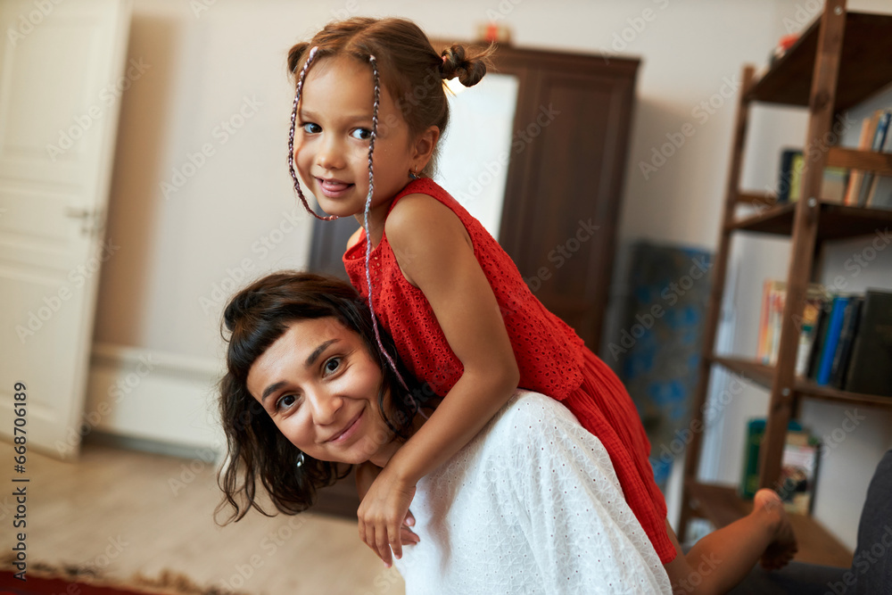 Side view of young beautiful baby sitter taking care of little girl ...