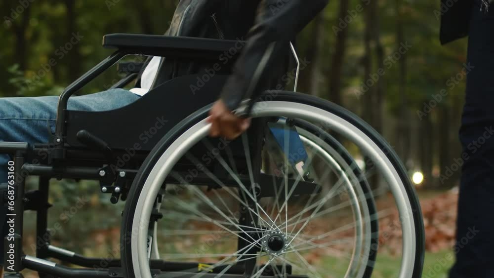 Disabled woman pushing the wheels of a wheelchair with her own hands ...