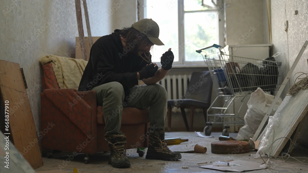Homeless poor man sitting in a room of an abandoned building filled ...